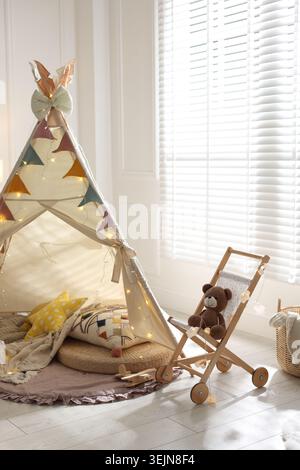 Cute wigwam with fairy lights and toys in stylish child's room Stock ...