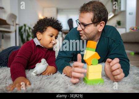 Father and child bonding while building a tower with toy blocks on the ...