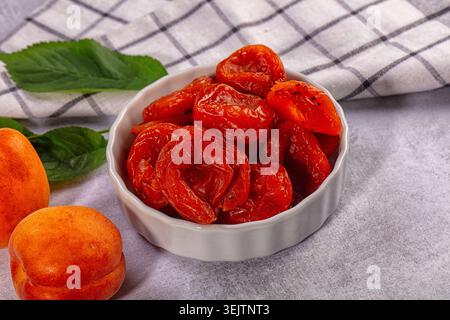 Vibrant orange dried apricots fill scalloped ceramic bowl on weathered ...