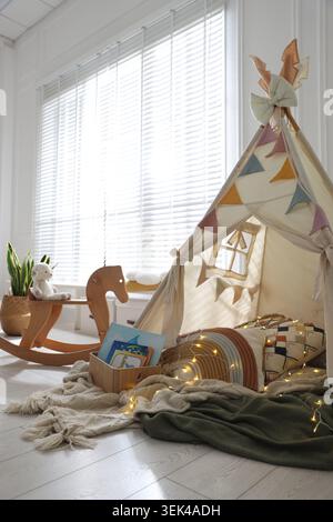 Cute wigwam with fairy lights and toys in stylish child's room Stock ...