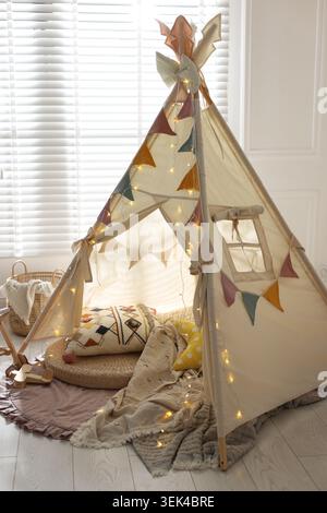 Cute wigwam with fairy lights and toys in stylish child's room Stock ...