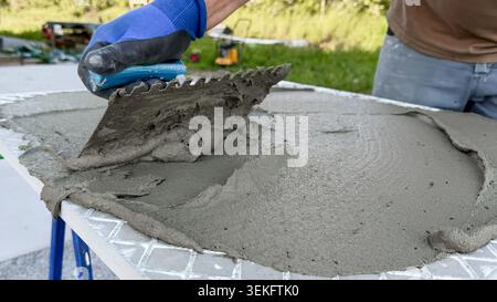 Construction worker applying cement mixture with trowel on tile surface ...