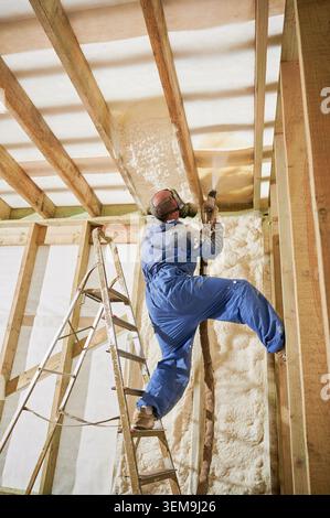 Worker in protective suit applying white paint to a boat interior using ...