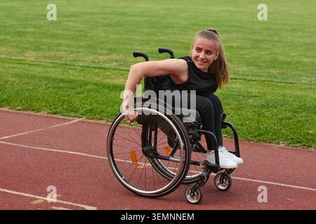 Smiling Female Wheelchair Athlete and Coach on Outdoor Running Track at ...