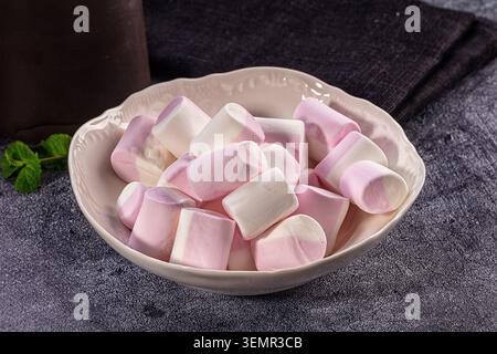 Pink white marshmallows piled in textured ceramic bowl with mint leaf ...