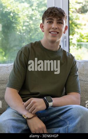 Relaxed teen boy sitting on chair in white studio space Stock Photo - Alamy