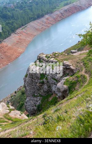 Mountain river flowing into Charvak reservoir under hazy hills in ...