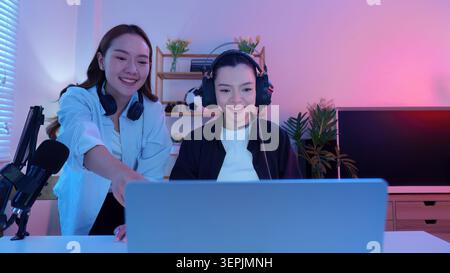 Two women gaming and streaming with laptop keyboard headset and ...