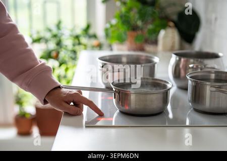 Pots filled with water heating on electric stove in kitchen, planned ...