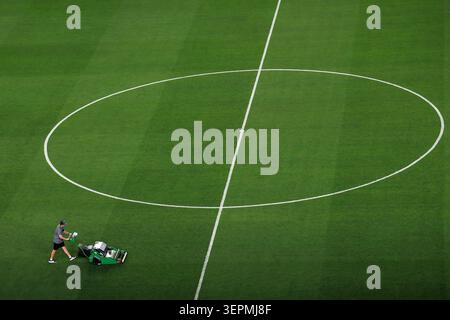 A groundsman cuts the grass of the pitch next to the center circle of ...