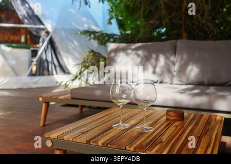 Luxury glamping terrace with wine glasses and outdoor lounge furniture ...
