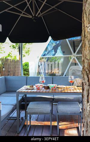 Luxury glamping terrace with wine glasses and outdoor lounge furniture ...