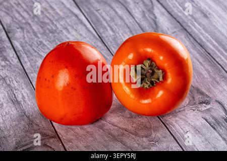 Vibrant orange persimmons with glossy skin dried calyx rest on muted ...