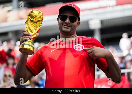 A fan of Canada lifts a replica of the World Cup trophy prior to the ...