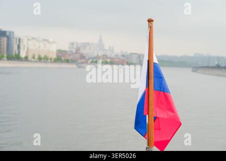 Russian flag waving near a river with city skyline and buildings ...