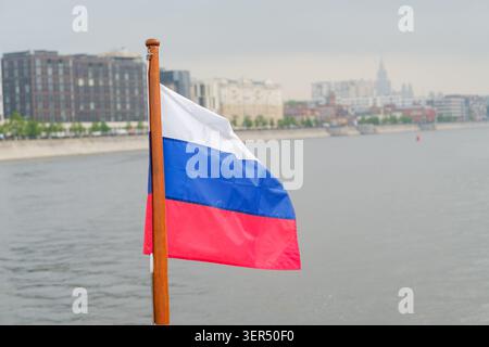 Russian flag waving near a river with city skyline and buildings ...