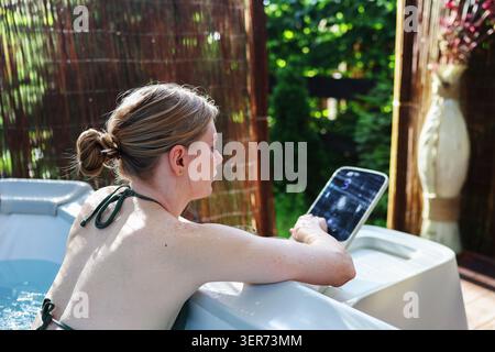 Outdoor spa lifestyle concept with woman using digital hot tub controls ...