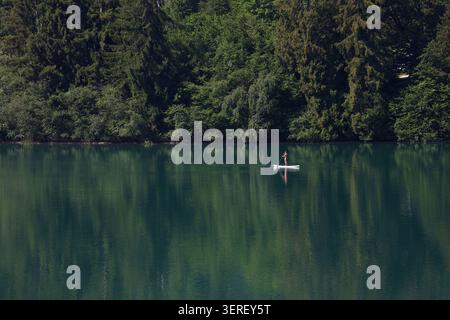 18 June 2026, Bavaria, Roßhaupten: A woman is paddling across Lake ...