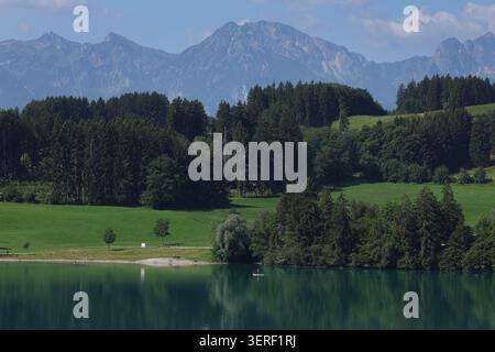18 June 2026, Bavaria, Roßhaupten: A woman is paddling across Lake ...