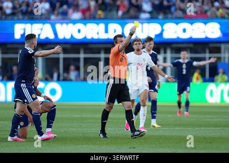 Referee Ilgiz Tantashev shows a yellow card to Scotland's Andy ...
