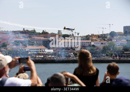 Spectators watch from the riverbank as an aerobatic aircraft performs a ...