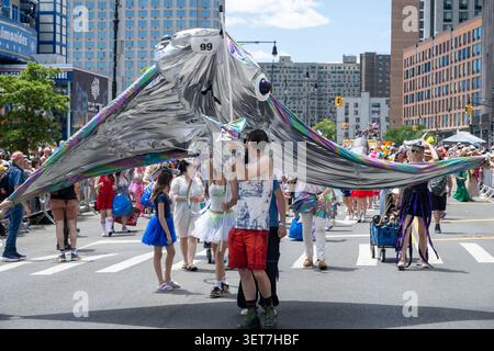 Revelers hold balloon in the shape of a sea creature participate in the ...