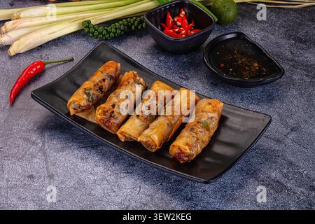 Five golden brown fried spring rolls arranged diagonally on textured ...