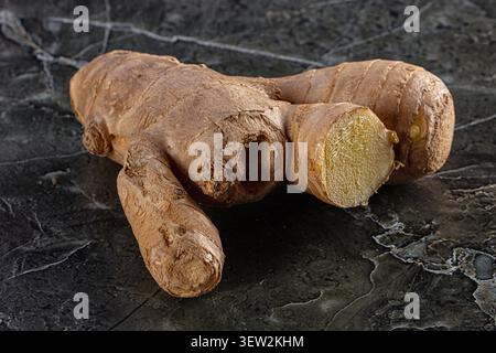 Fresh ginger root with exposed yellow interior placed on weathered ...