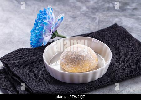Mochi dusted with powdered sugar sits on blue white ceramic plate ...