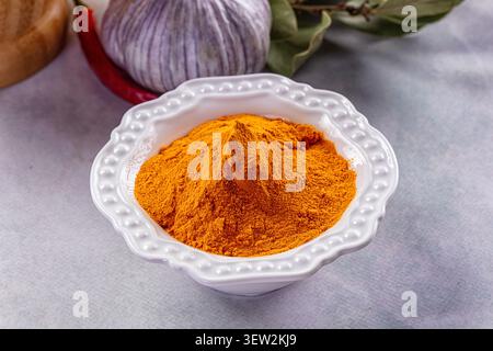 Vibrant orange turmeric powder piled in white ceramic bowl surrounded ...
