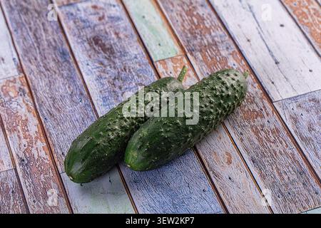 Two ripe green cucumbers with bumpy skin arranged diagonally on light ...