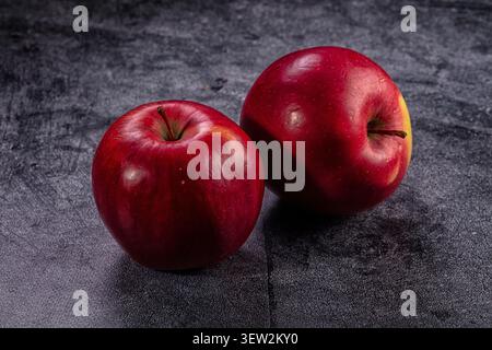 Two shiny red apples rest on weathered wood surface. Warm lighting ...