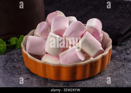 Pink white marshmallows piled in textured ceramic bowl with mint leaf ...
