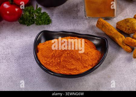Vibrant orange turmeric powder piled in white ceramic bowl surrounded ...