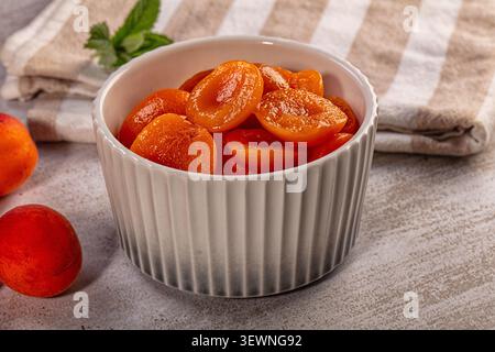 Vibrant orange dried apricots fill scalloped ceramic bowl on weathered ...