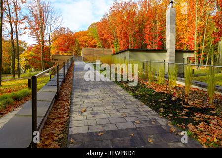 A paved walkway leads through a park square adorned with trees ...