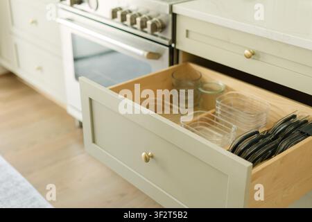 Open kitchen pantry drawer with glass storage jars filled with colorful ...