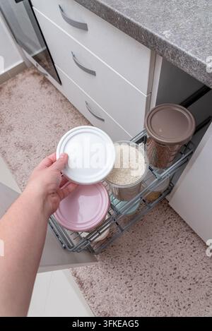 Open kitchen pantry drawer with glass storage jars filled with colorful ...