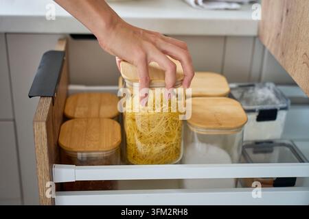 Open kitchen pantry drawer with glass storage jars filled with colorful ...