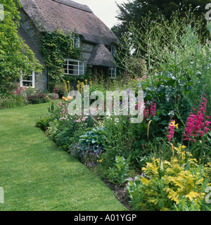 Path beside summer flowering border in front of traditional timbered ...