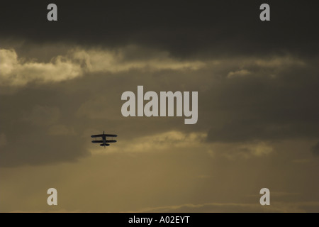 A small biplane flying towards an incoming storm Stock Photo - Alamy