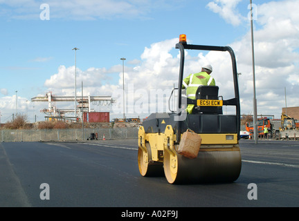 Roller rolling macadam tarmac to make a level surface for a car park ...