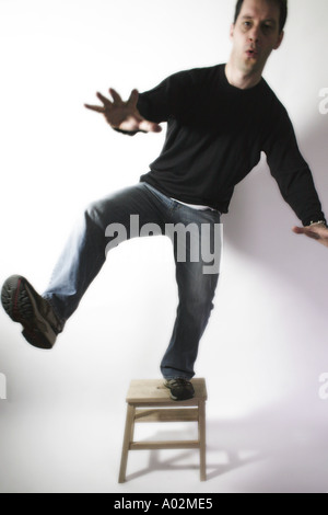 Man stood on stool losing his balance and about to fall over Stock ...
