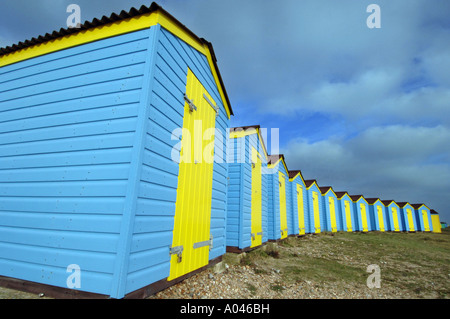 A row of freshly painted traditional seaside beach huts on the shore at ...
