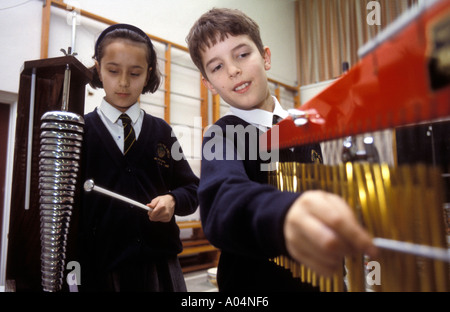 School children playing percussion instruments in an English classroom ...