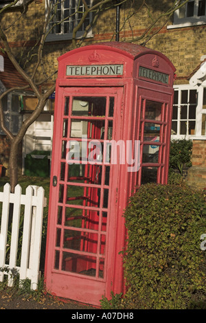 A red pink rural telephone box half hidden by overgrown fern plants on ...