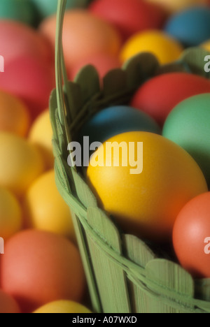 Multi colors Easter eggs in the woven basket on colored background ...