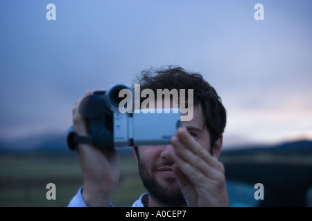 Young man using a video camera Stock Photo - Alamy