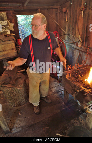 A blacksmith pumps more air into the coal fed fire to make it burn ...