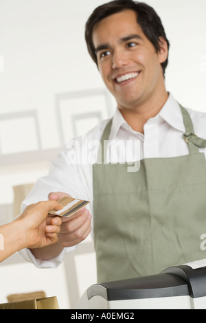 Young hispanic shopkeeper man smiling happy holding dataphone at ...